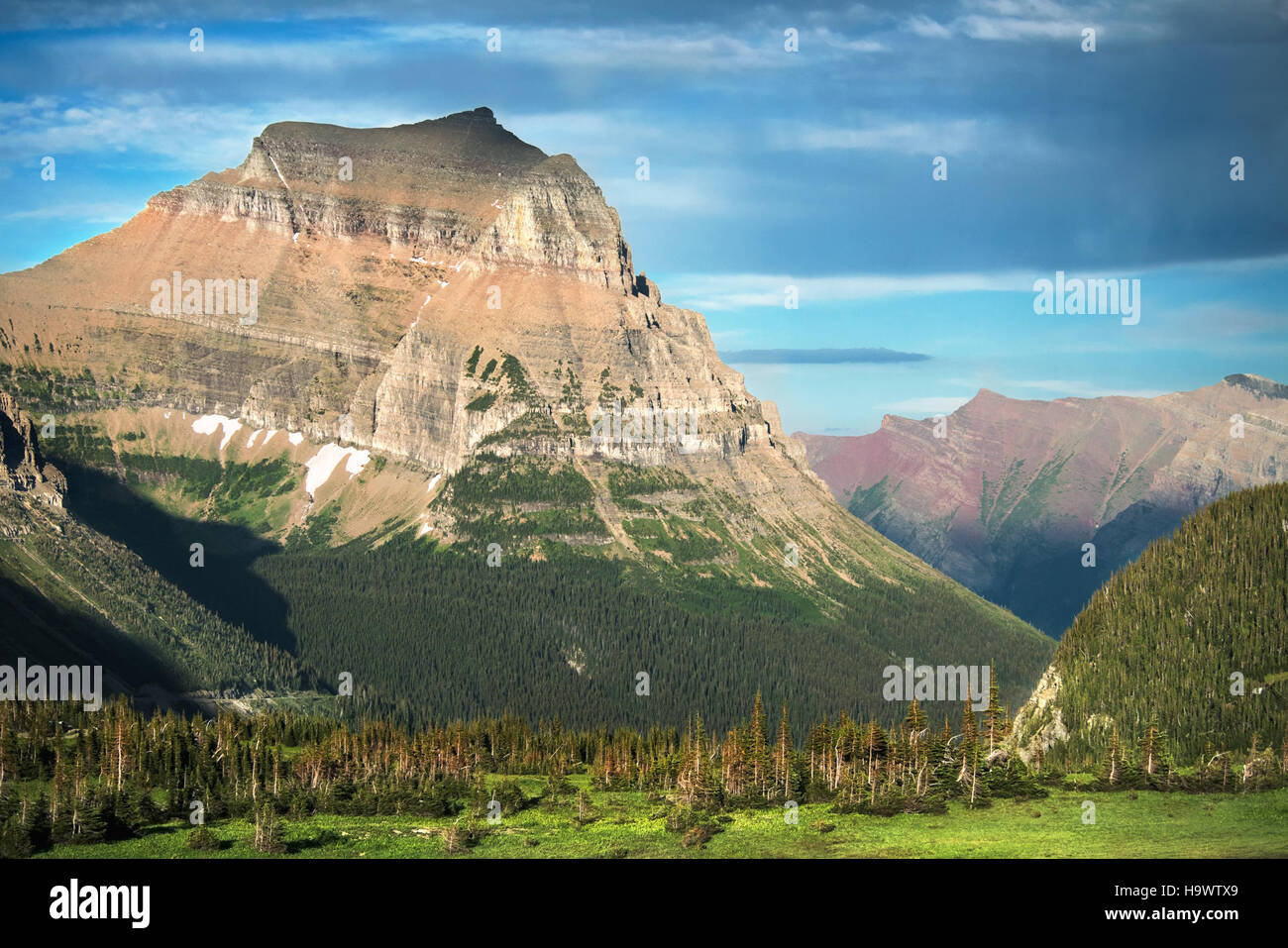 The setting sun over Glacier National Park offers a stunning view of ...