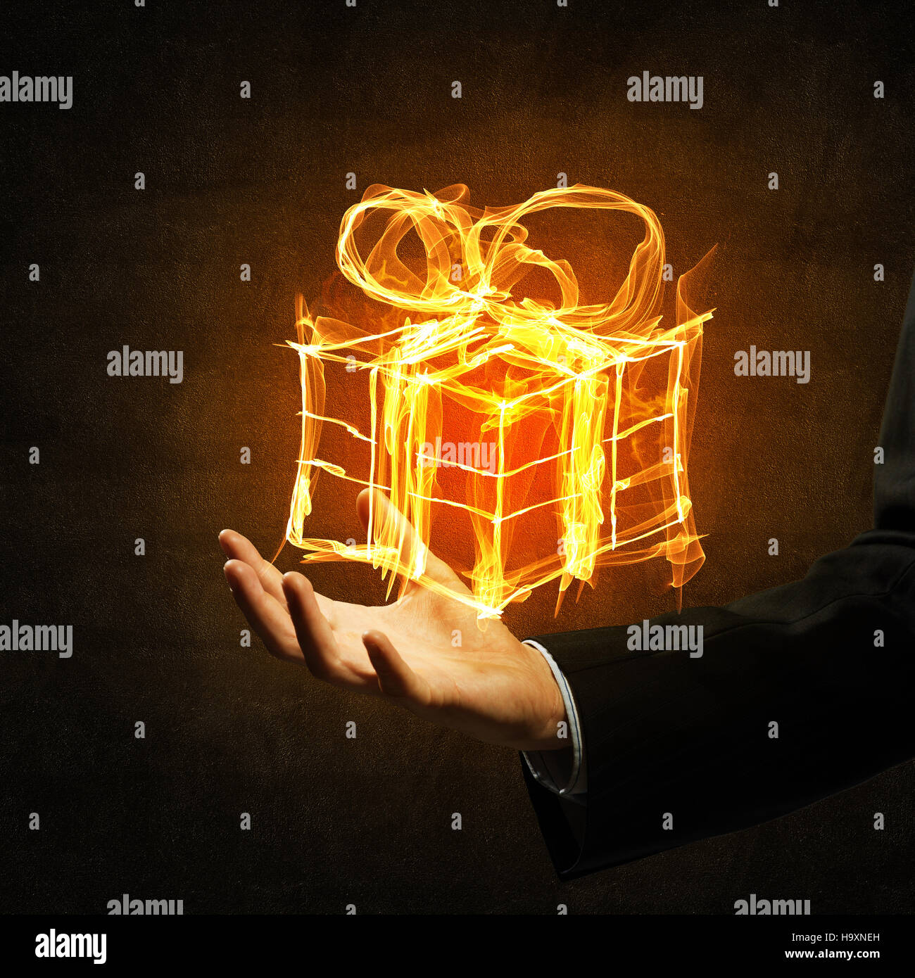 Glowing fire gift box icon in palm on dark background Stock Photo - Alamy