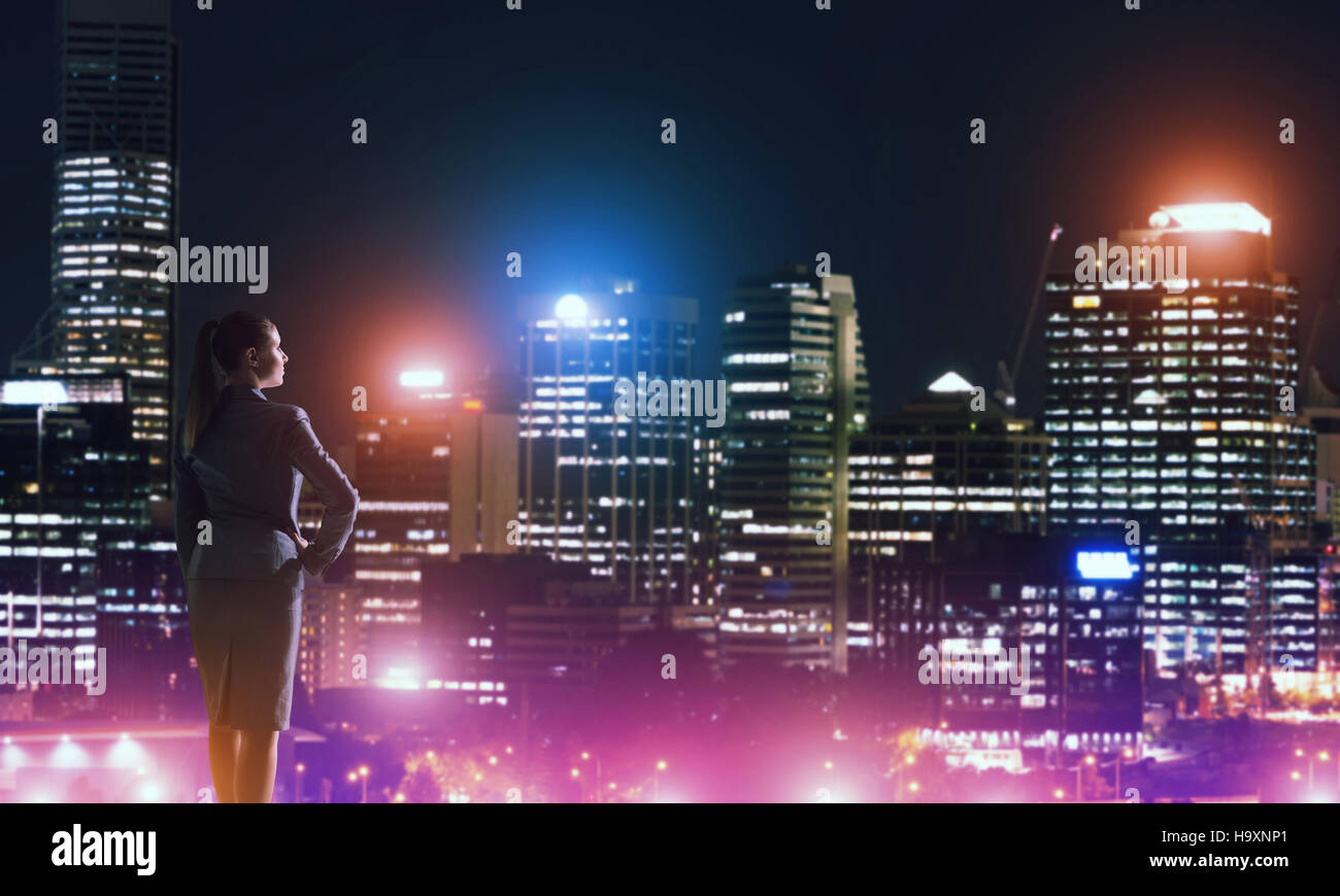 Rear view of elegant businesswoman viewing lights of night city Stock ...