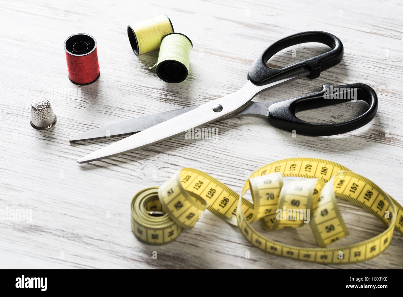 Old scissors bobbins threads and tape on wooden table Stock Photo - Alamy