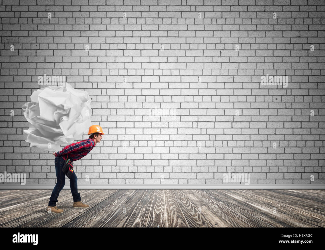 Builder man carrying paper ball on his back Stock Photo - Alamy