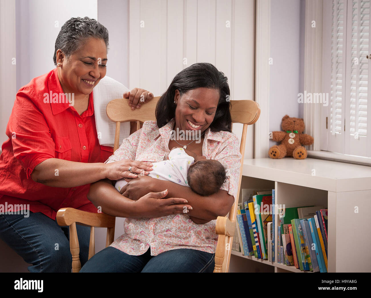 This image depicts a family moment with a mother, grandmother, and baby ...