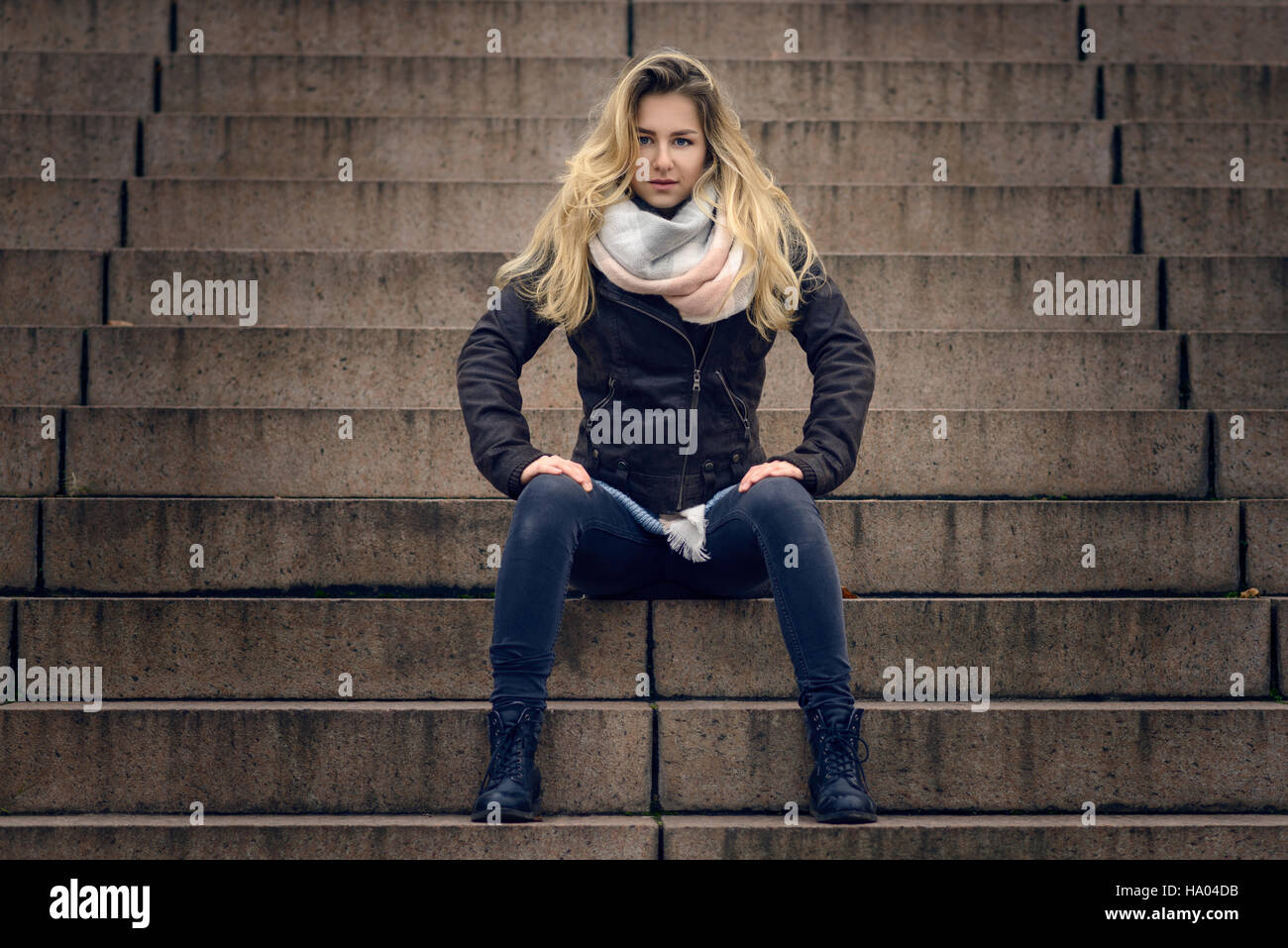 Smiling stylish woman in a dark slack suit sitting on a flight of ...