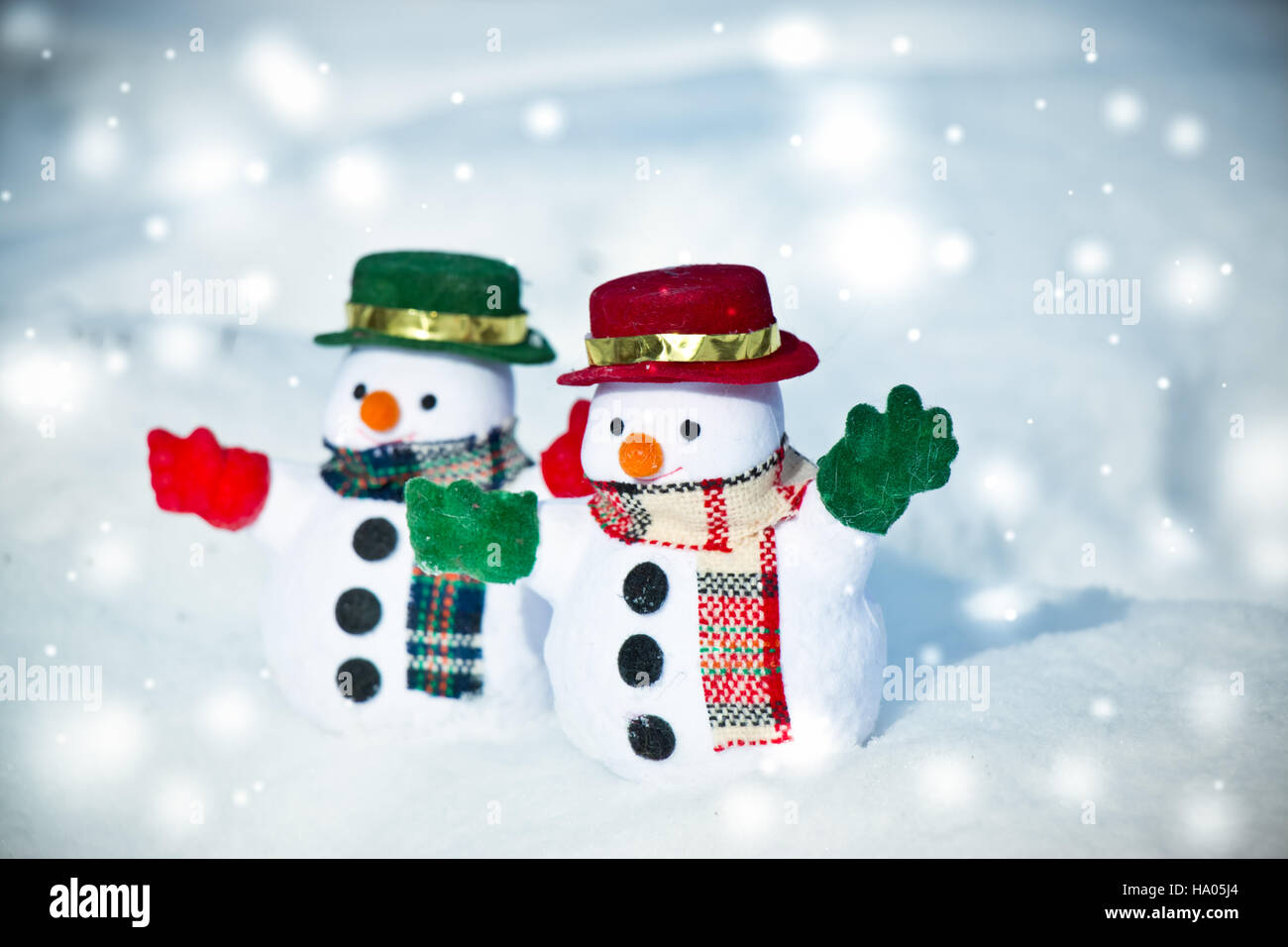 Snowman and friend stand among pile of snow in park. Morning sunshine ...