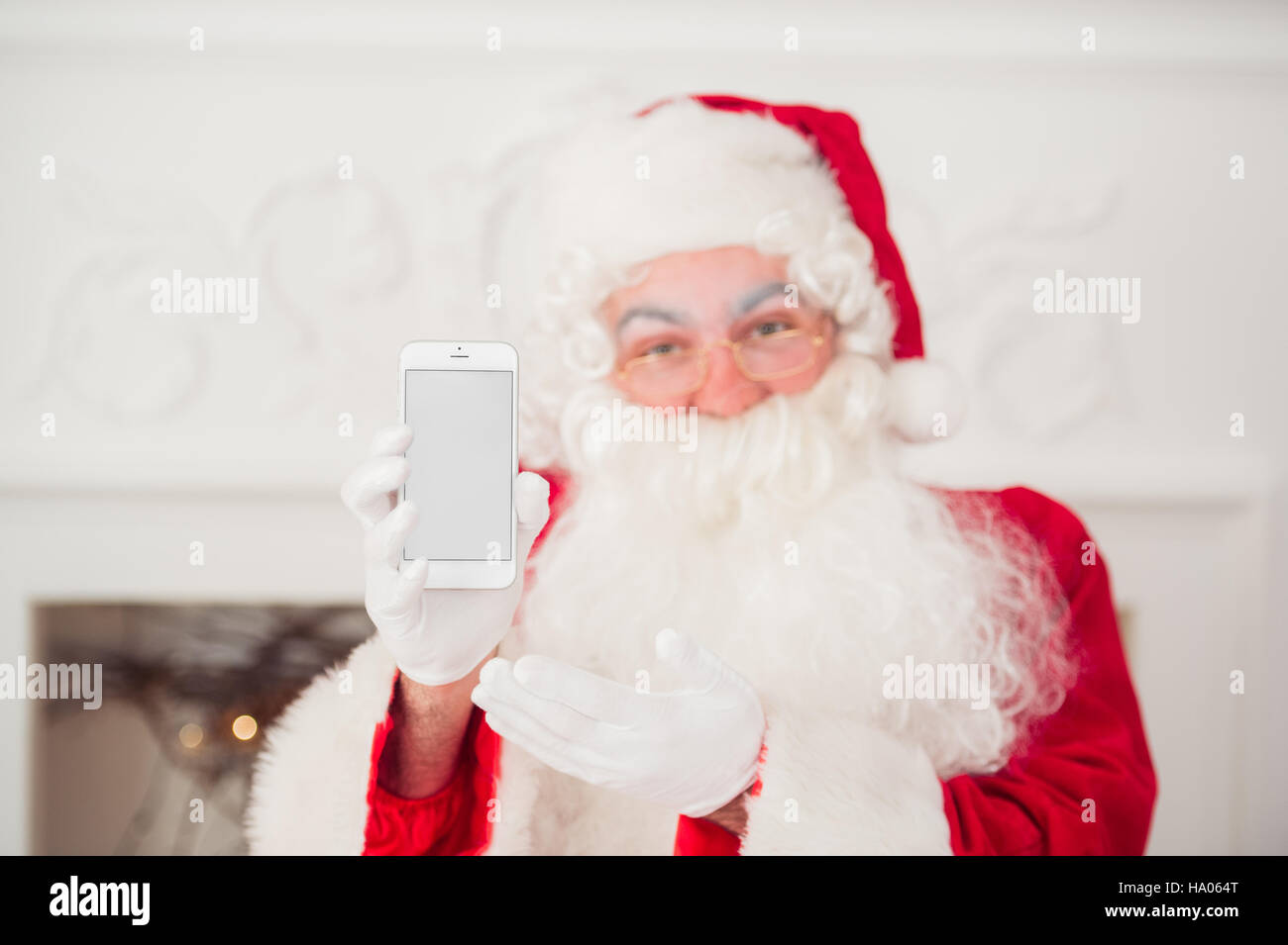 Santa Claus shows a smartphone against red background Stock Photo - Alamy