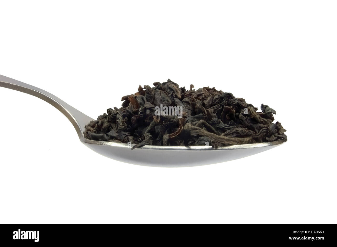 Teaspoon with dark black loose tea leaf, isolated spoonful macro ...