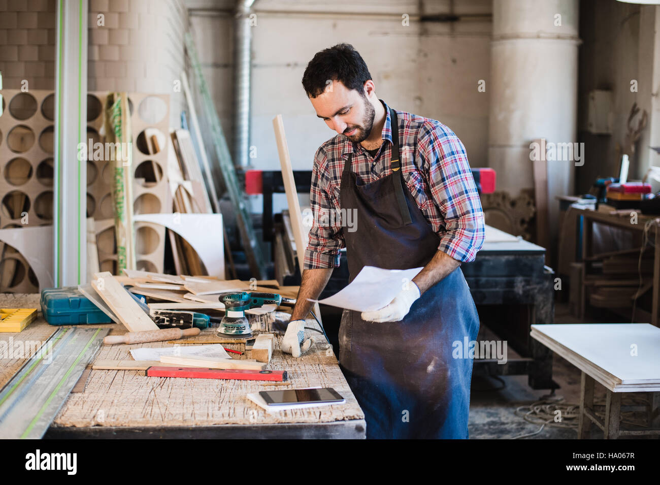 Portrait of a carpenter standing in his woodwork studio and holding ...