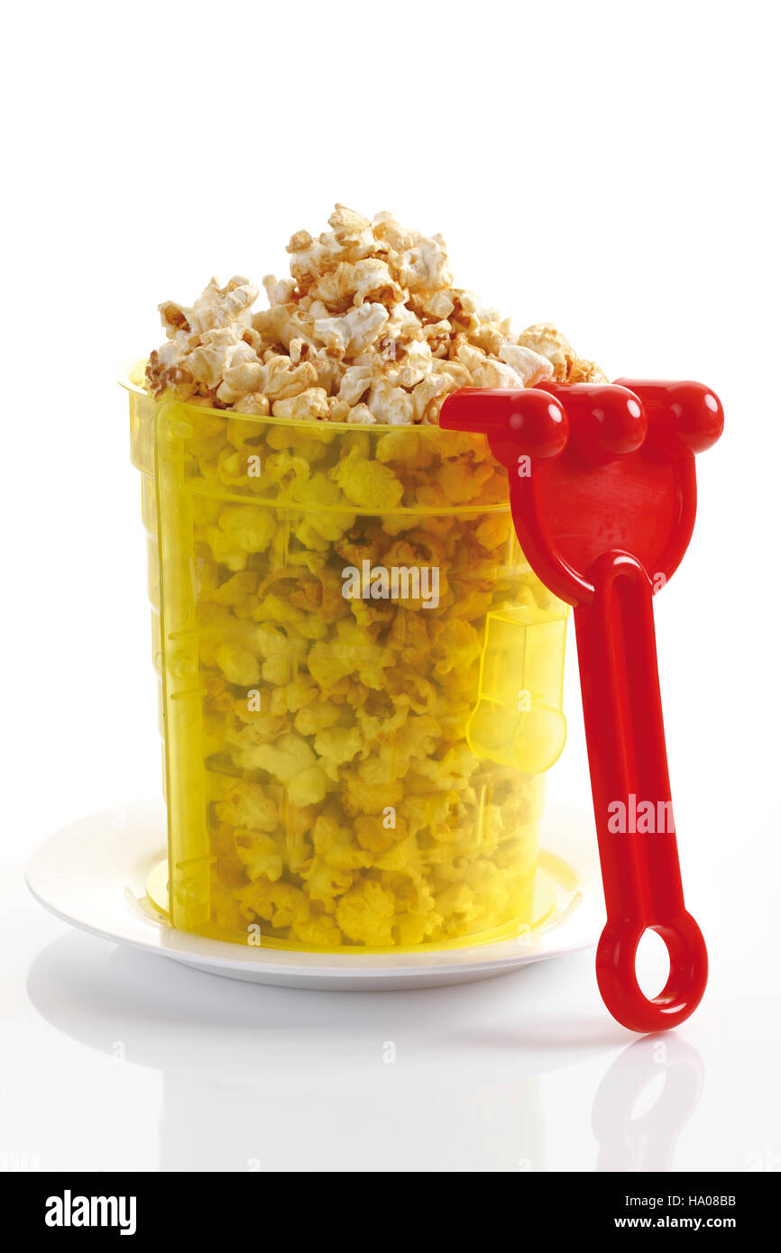 Popcorn in a yellow plastic bucket and a toy rake Stock Photo - Alamy
