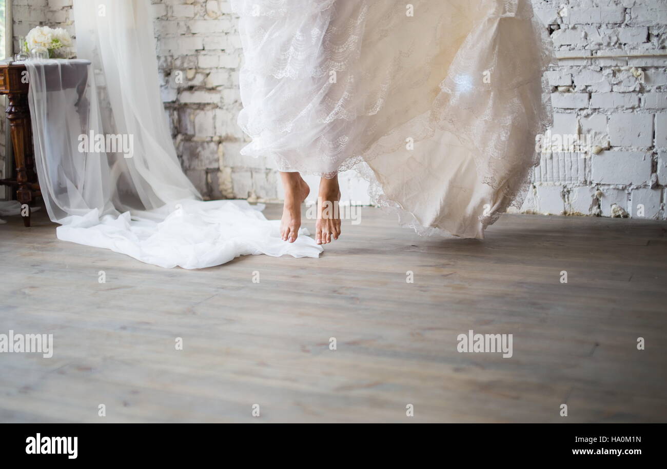 Bride jumping barefoot in rustic white wedding dress. Beautiful wedding ...