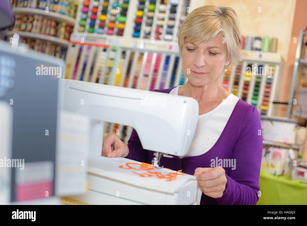 Lady using sewing machine in craft shop Stock Photo - Alamy