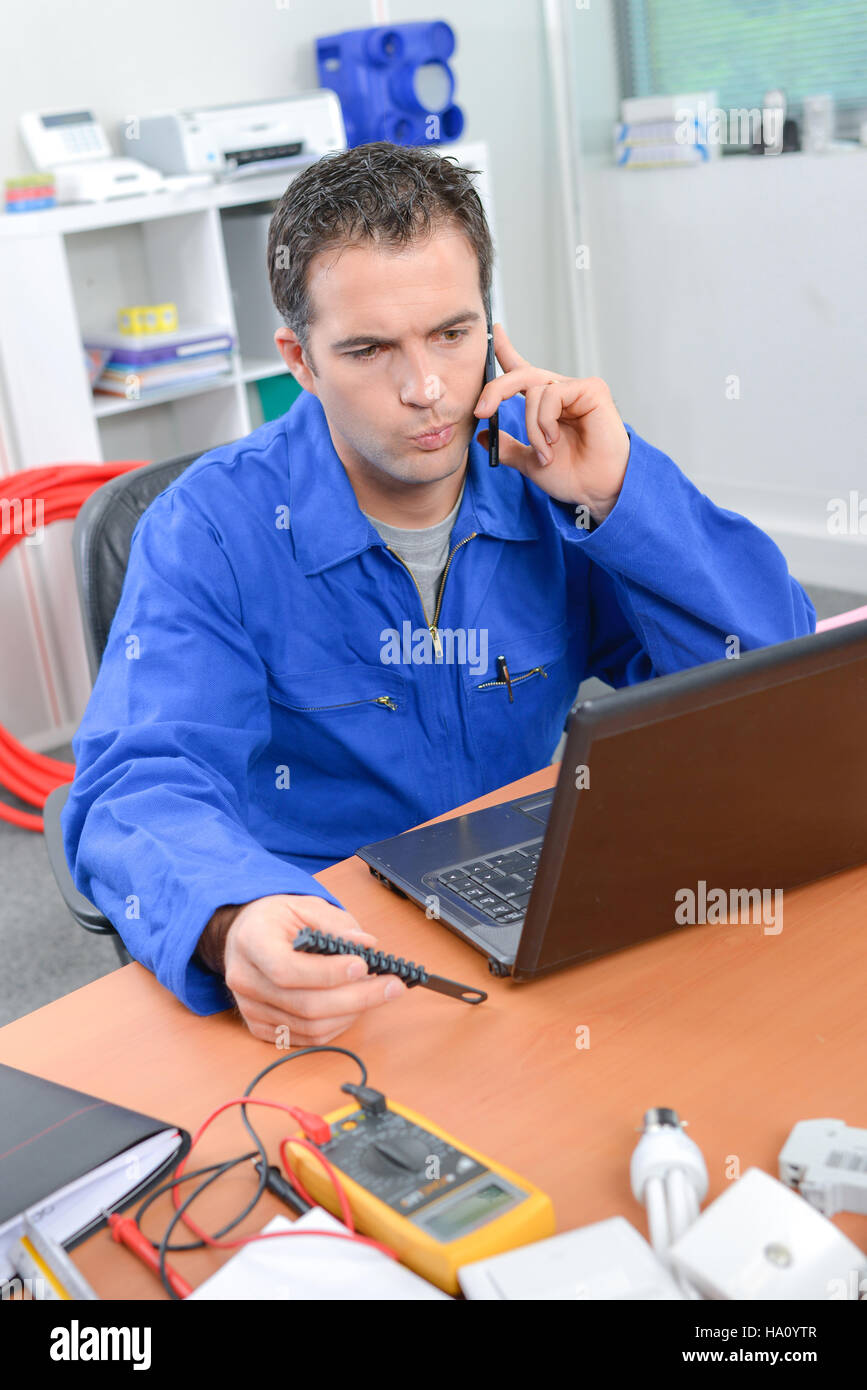 Workman on telephone with contemplative expression Stock Photo - Alamy