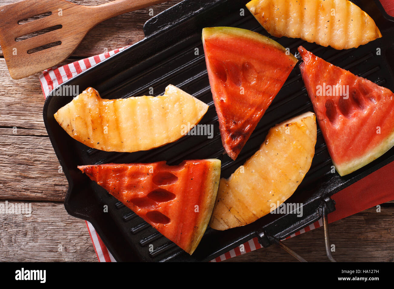 Slices of ripe watermelon and melon in a pan grill close-up on the ...