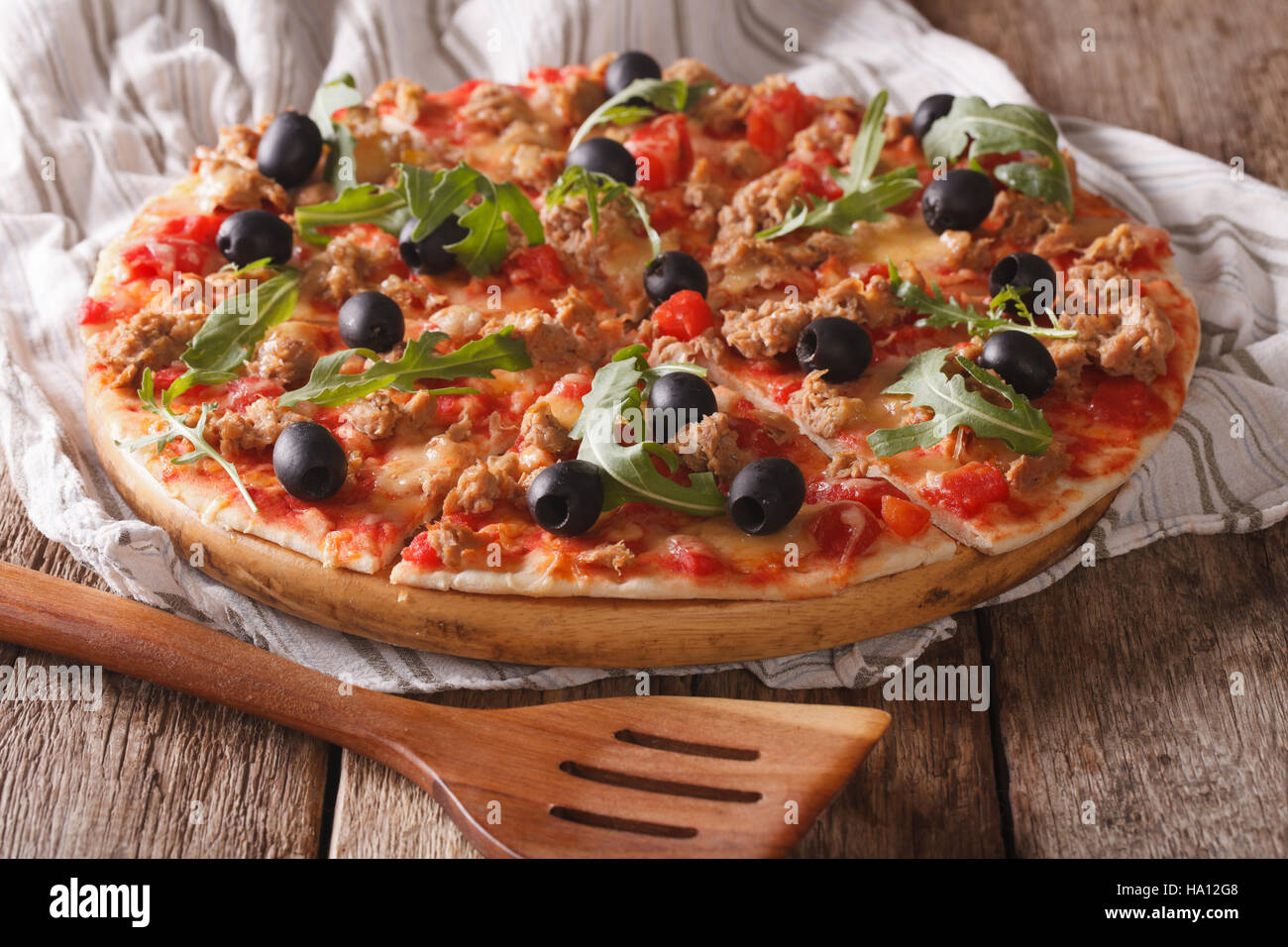 Fish Pizza with tuna, olives and arugula close-up on the table ...