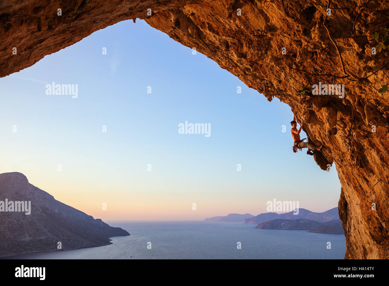 Young man climbing in cave at sunset Stock Photo - Alamy