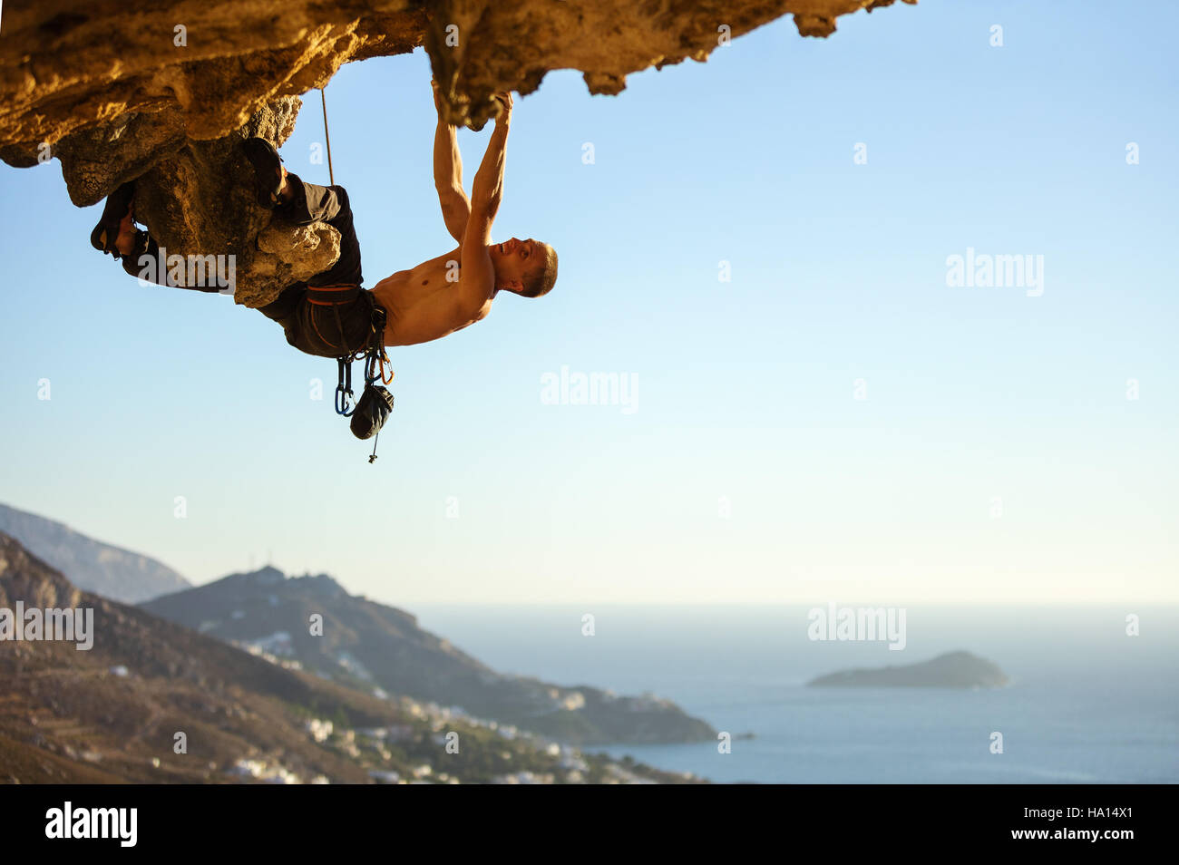 Young man climbing on roof in cave, view of coast below Stock Photo - Alamy