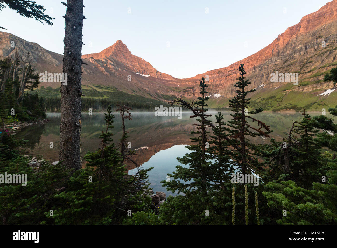 This image captures a tranquil sunrise over Oldman Lake in Glacier ...