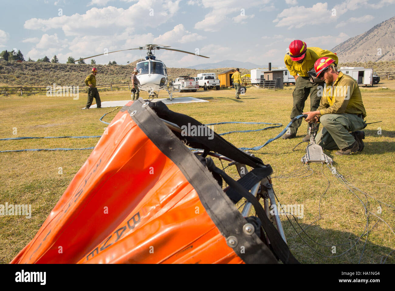 This image shows a Helitack crew preparing a helicopter for bucket ...