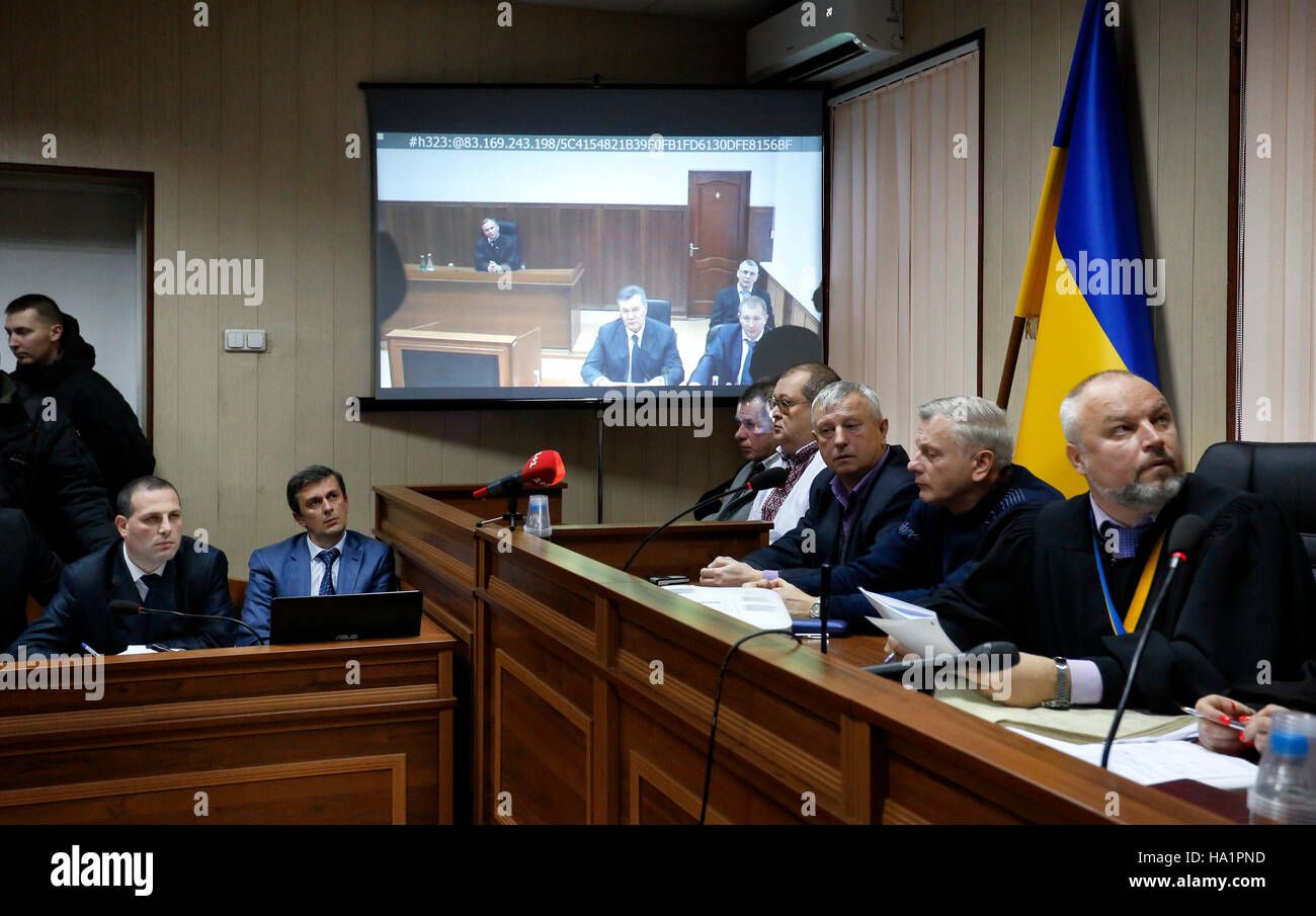 Ukrainian court members attend a hearing as a TV screen shows former ...