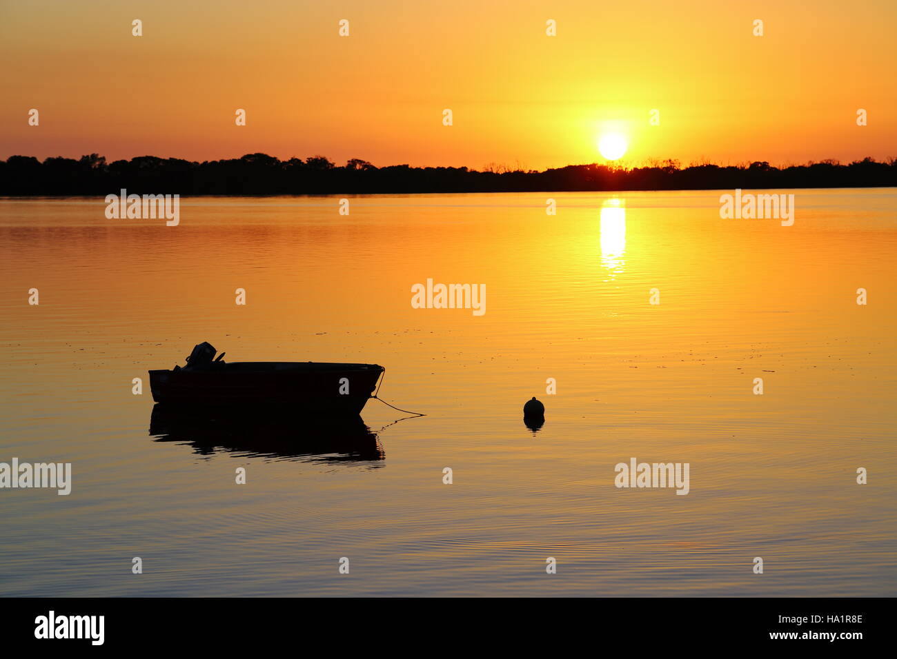 Sunrise and a boat at its mooring on Pumicestone Passage off Golden ...
