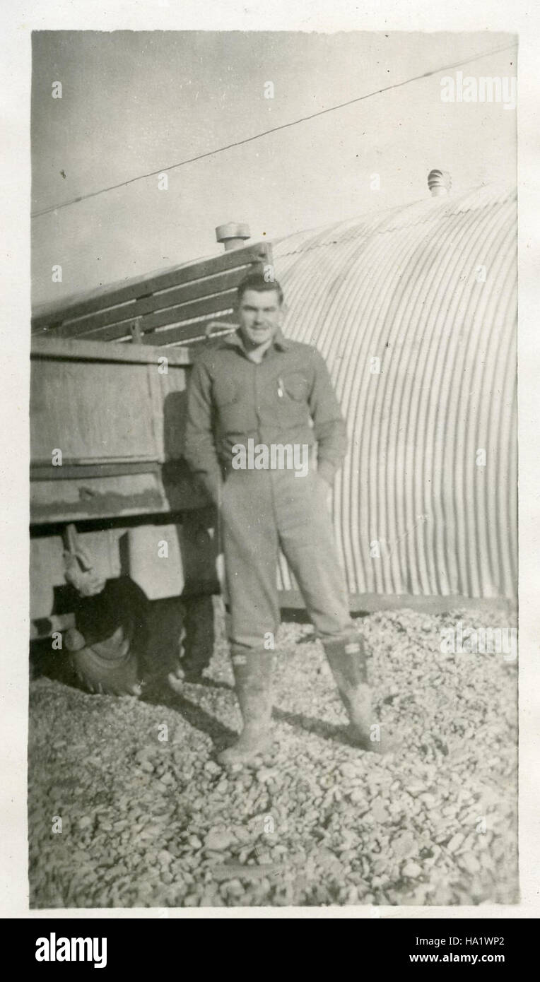 A man stands beside a Quonset hut in Alaska, a distinctive structure ...