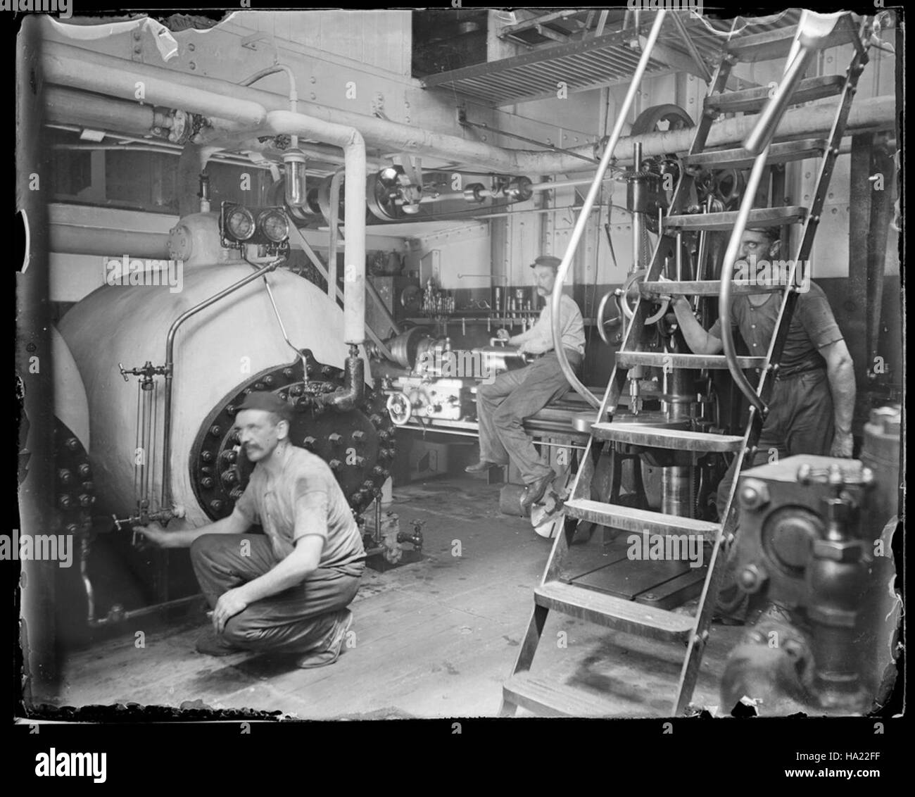 The image captures three crew members working in the engine room of the ...