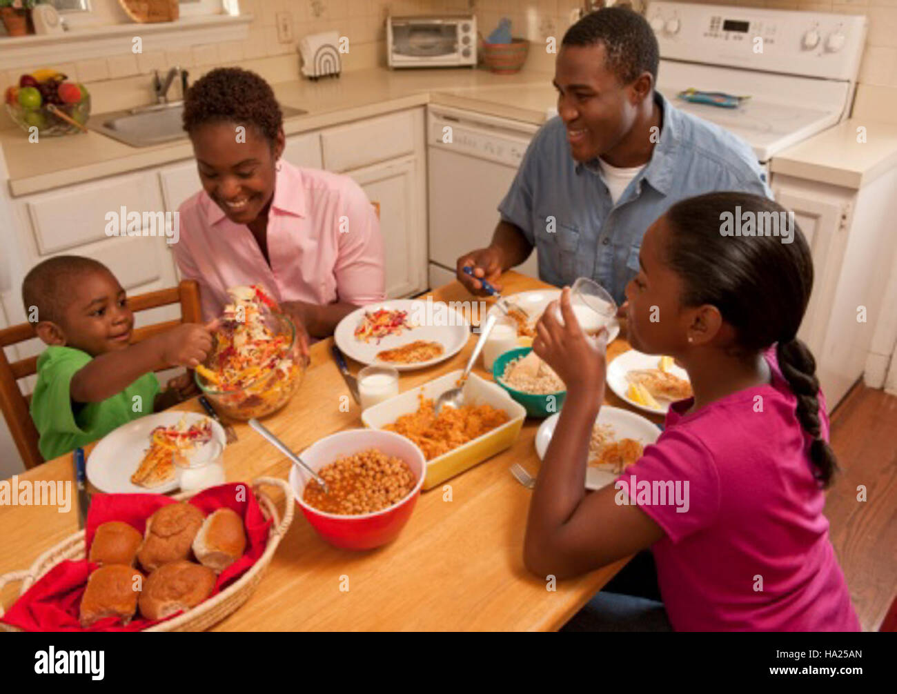 A family enjoys a meal together in their kitchen, illustrating a simple ...