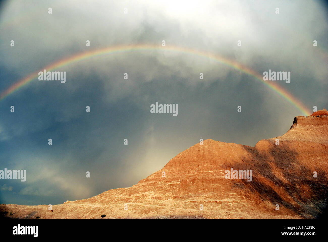 A rainbow arches over the rugged landscape of Badlands National Park ...