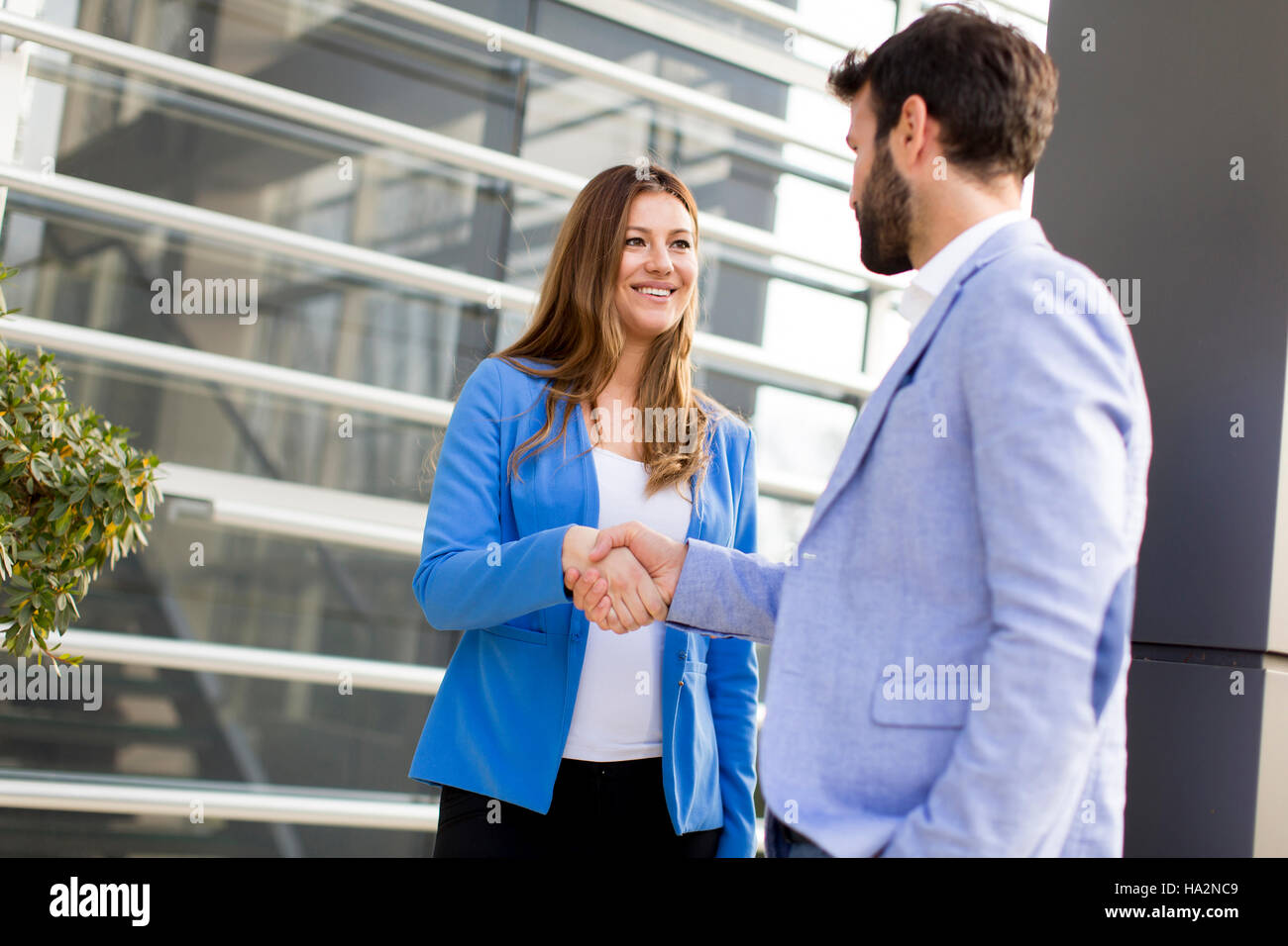 Young business people shake hands in front of the office building Stock ...