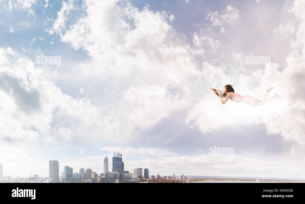 Young pretty woman flying in sky and playing fife Stock Photo - Alamy
