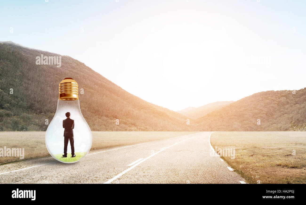 Young businessman trapped inside of light bulb on asphalt road Stock ...