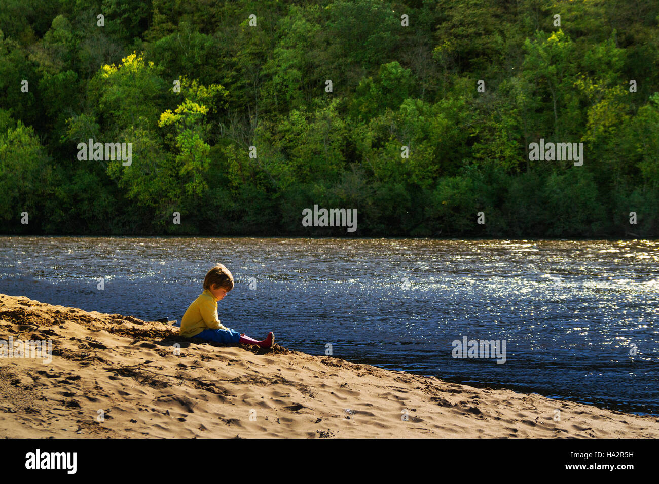 Boy sitting on beach by a lake Stock Photo - Alamy