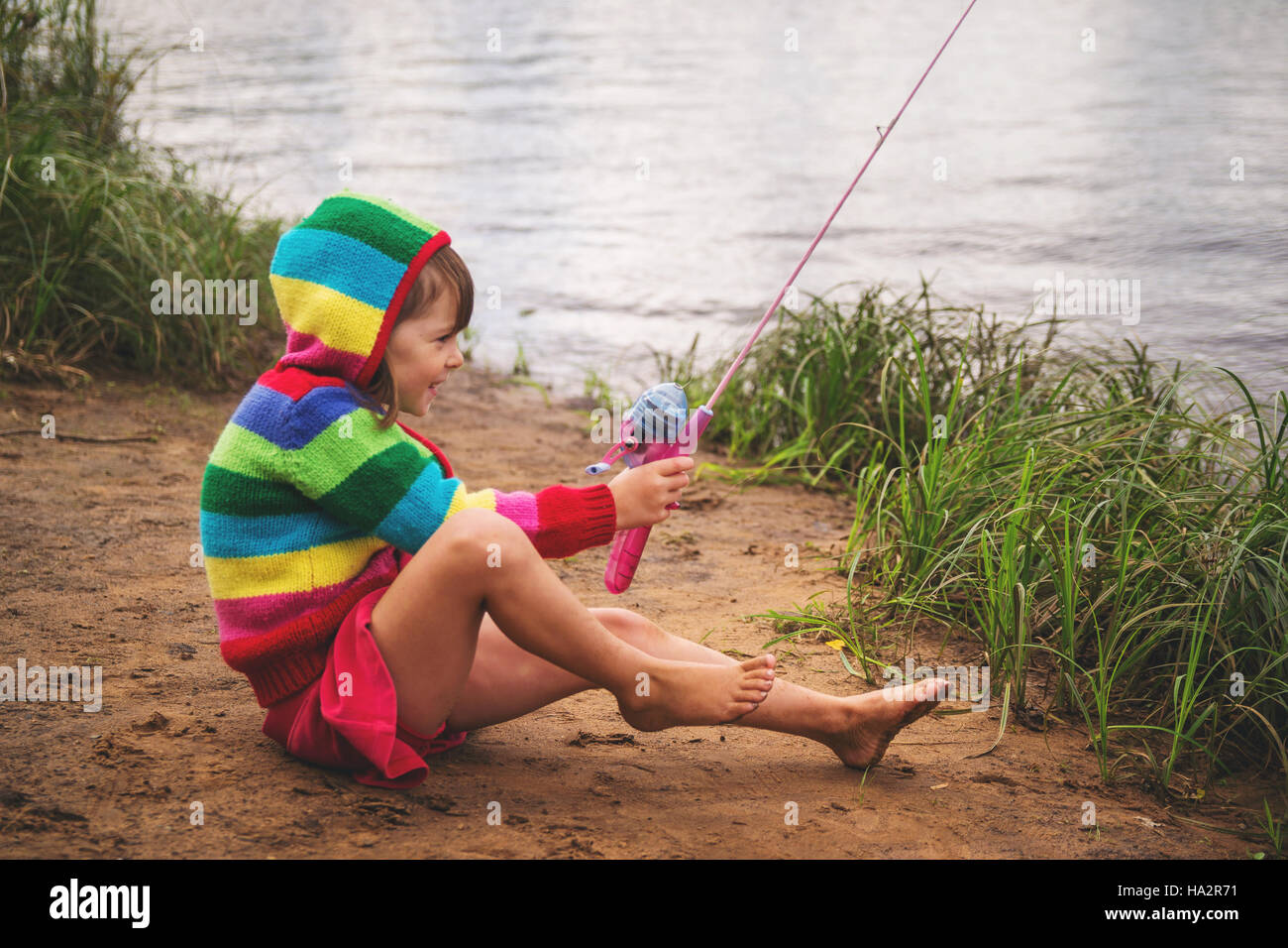 Girl sitting by river fishing Stock Photo - Alamy