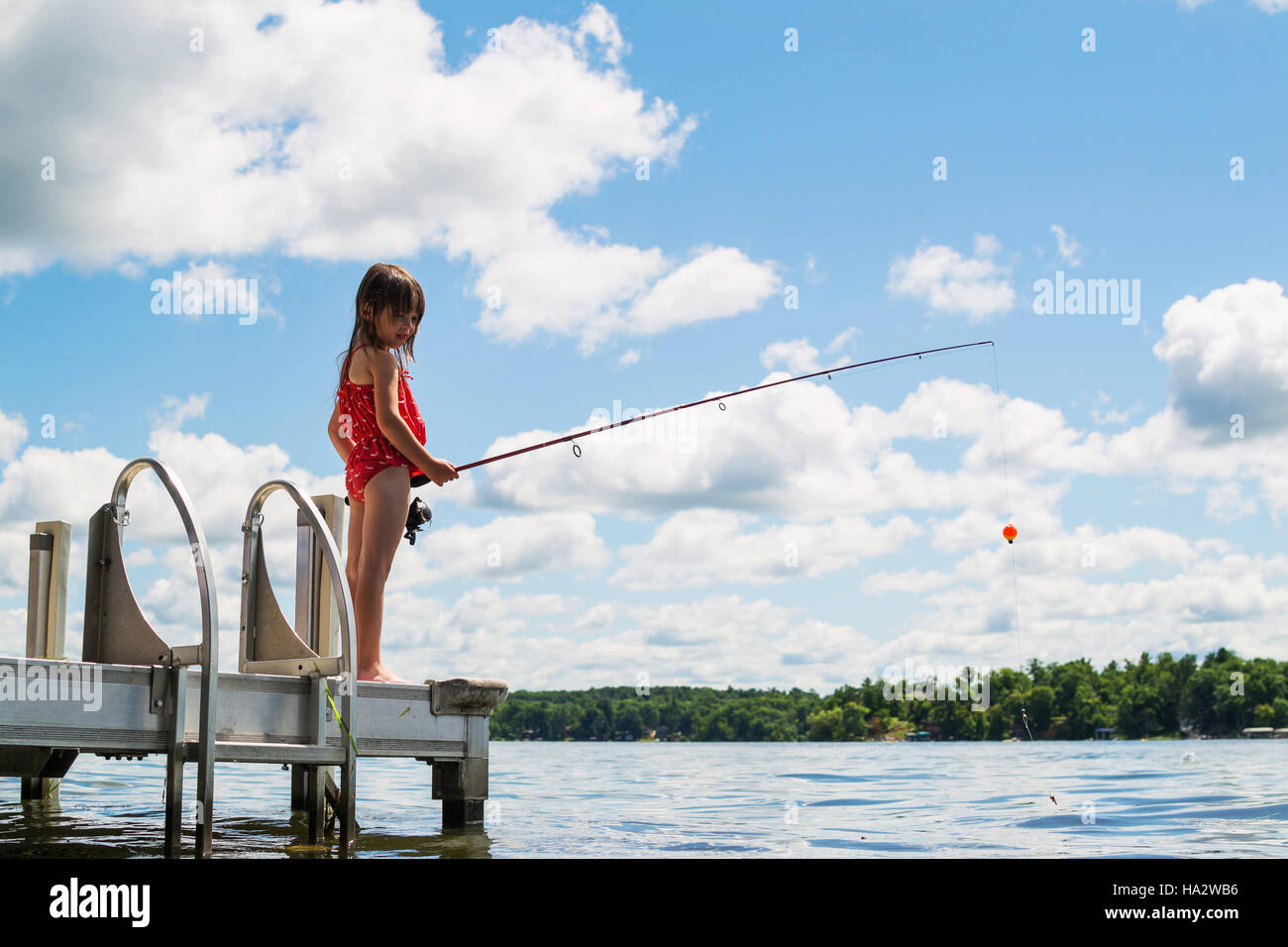 Girl standing on dock fishing Stock Photo - Alamy