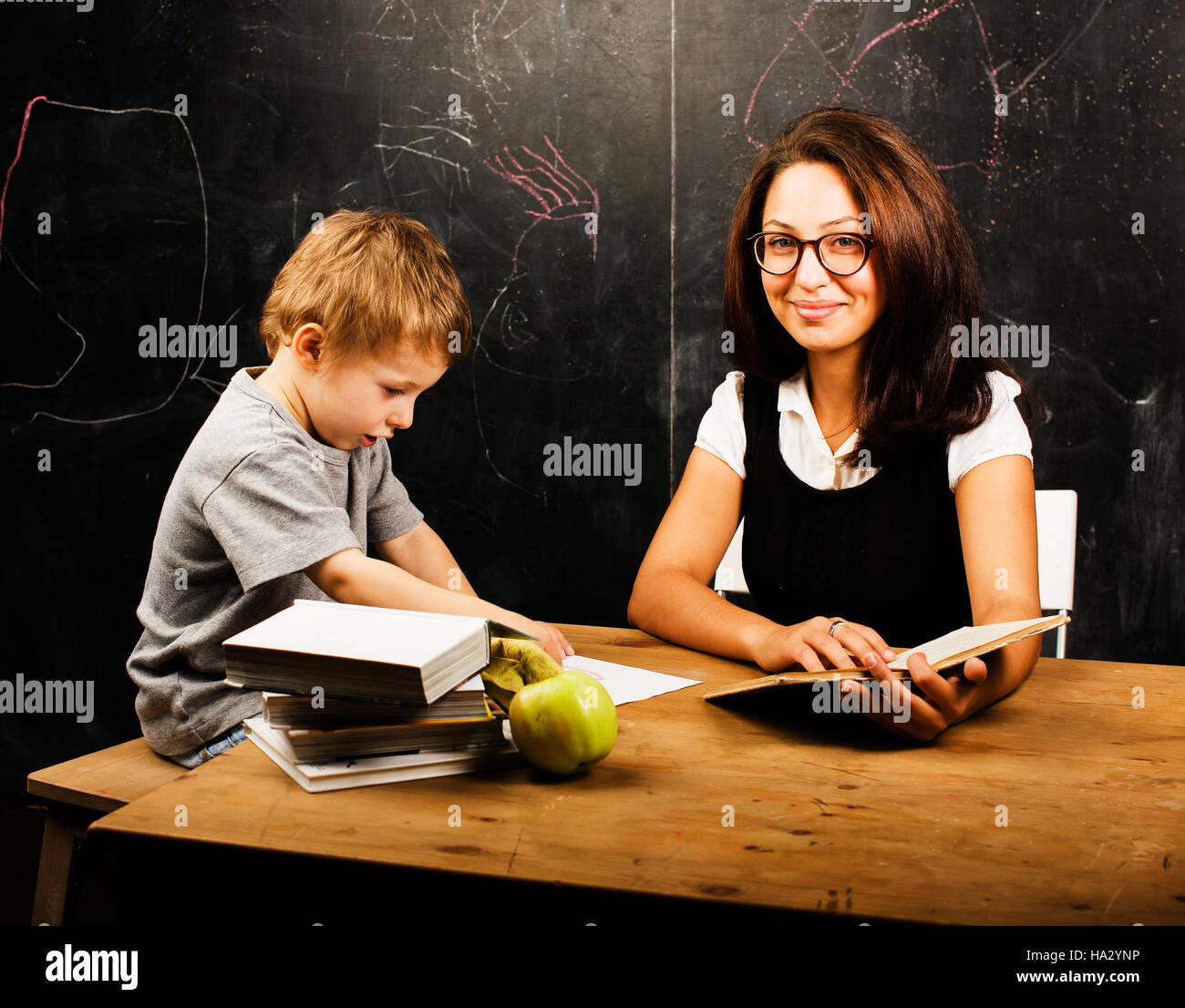 little cute boy with young teacher in classroom studying at blac Stock ...