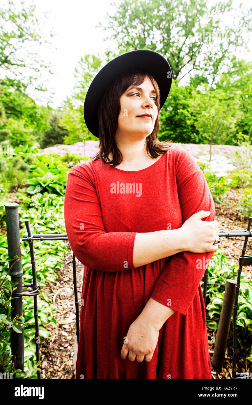 mature brunette woman in green garden wearing hat, smiling, frie Stock ...