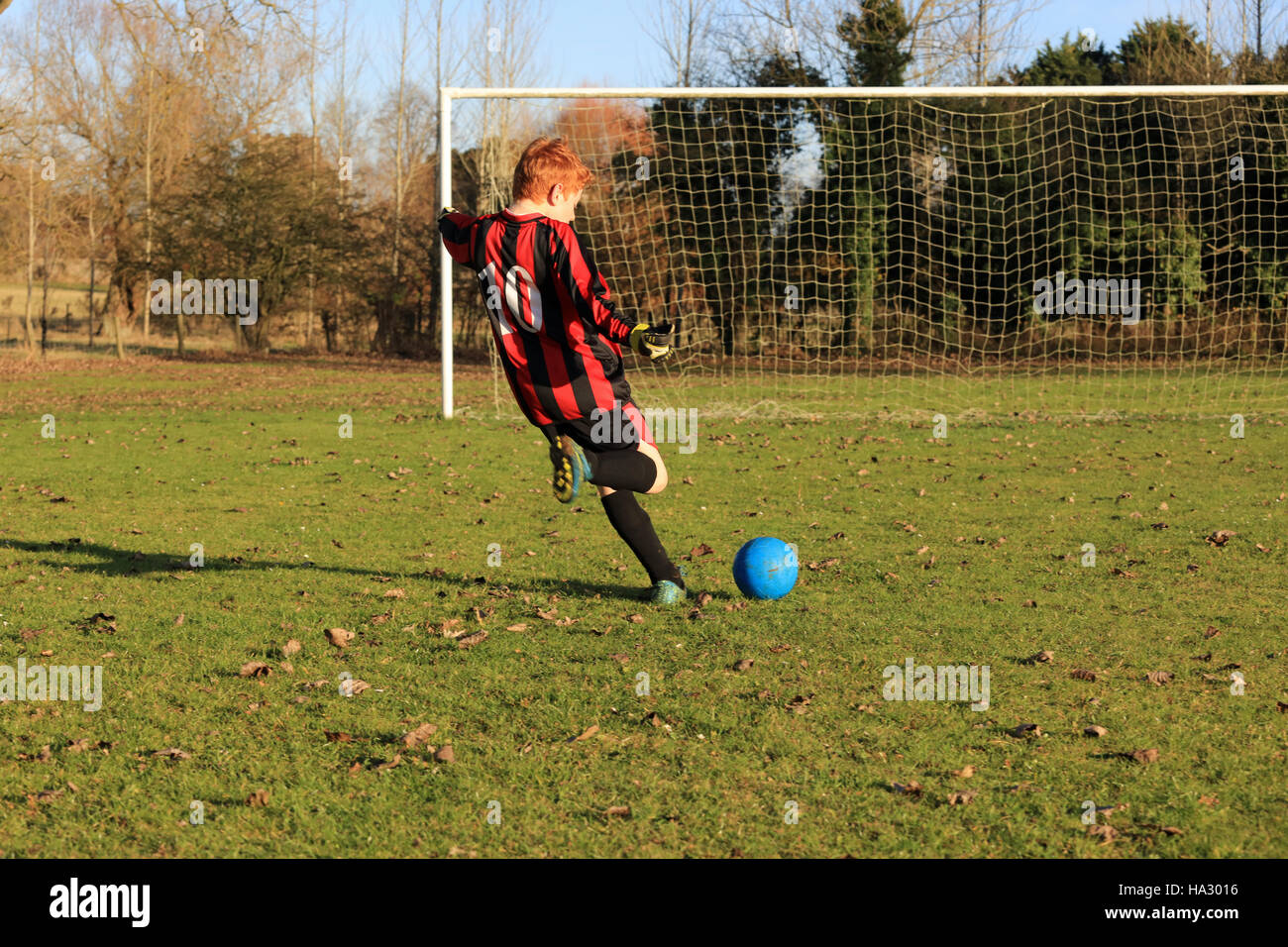 Boy practicing taken penalty kick on a football pitch, England, UK ...