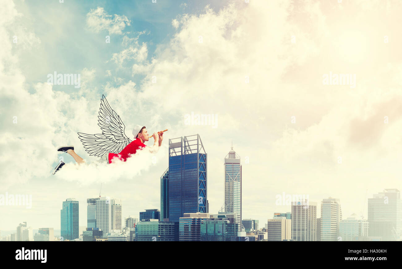 Young cheerful man flying high above city and playing fife Stock Photo ...