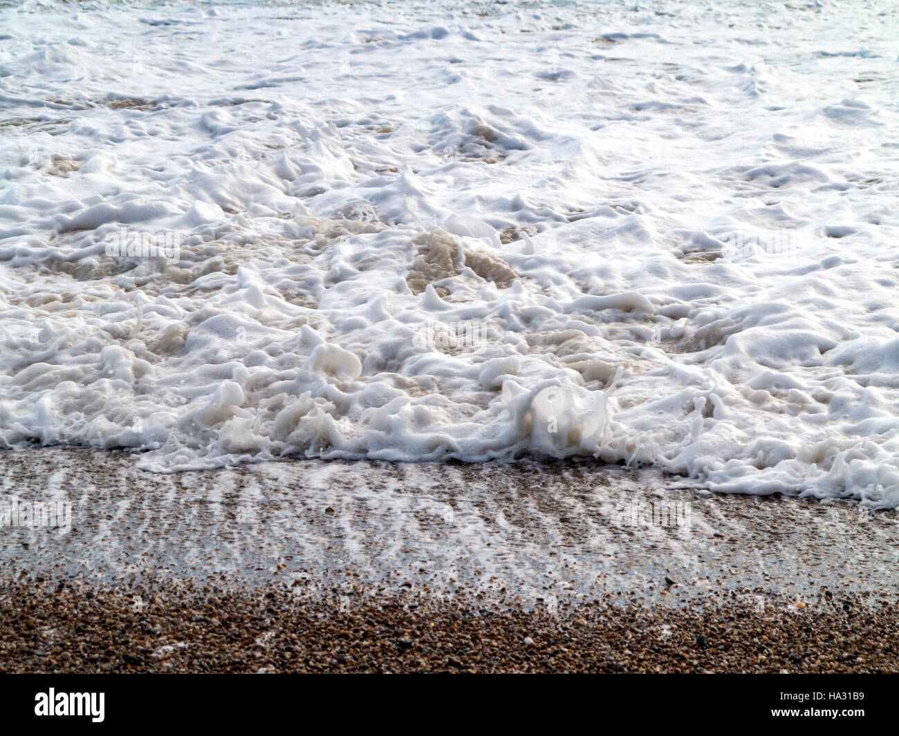 Tidal froth on a pebble beach shoreline during heavy seas Stock Photo ...