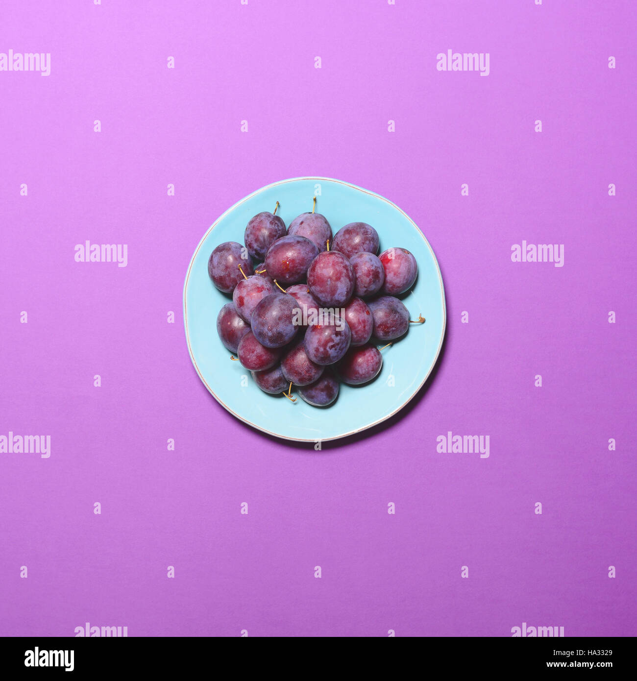 Top view of fresh plums in blue plate on lilac background - Flat lay ...