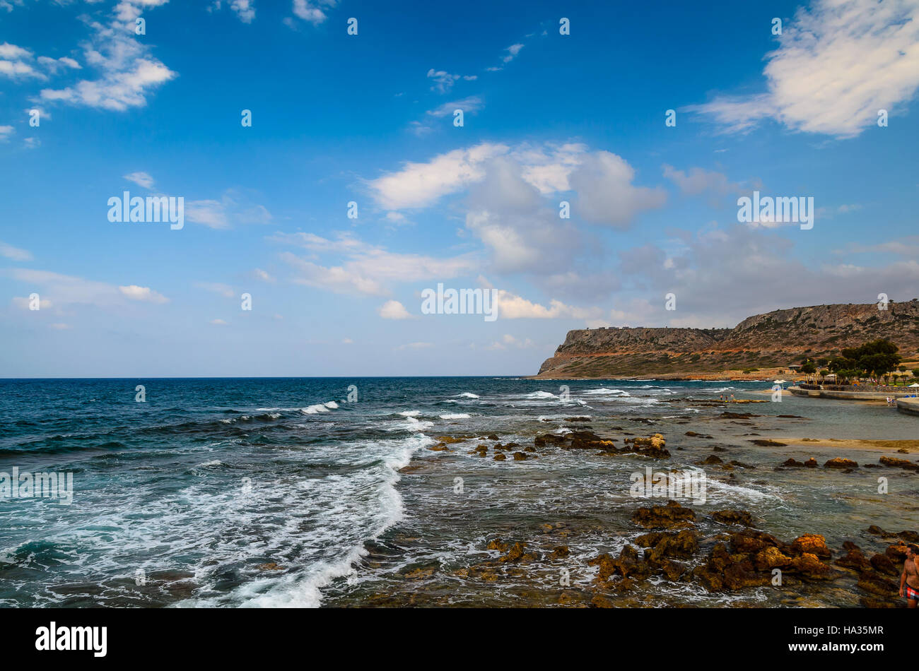 Beautiful Cretan rocky coastline with blue sea and surfers at the ...