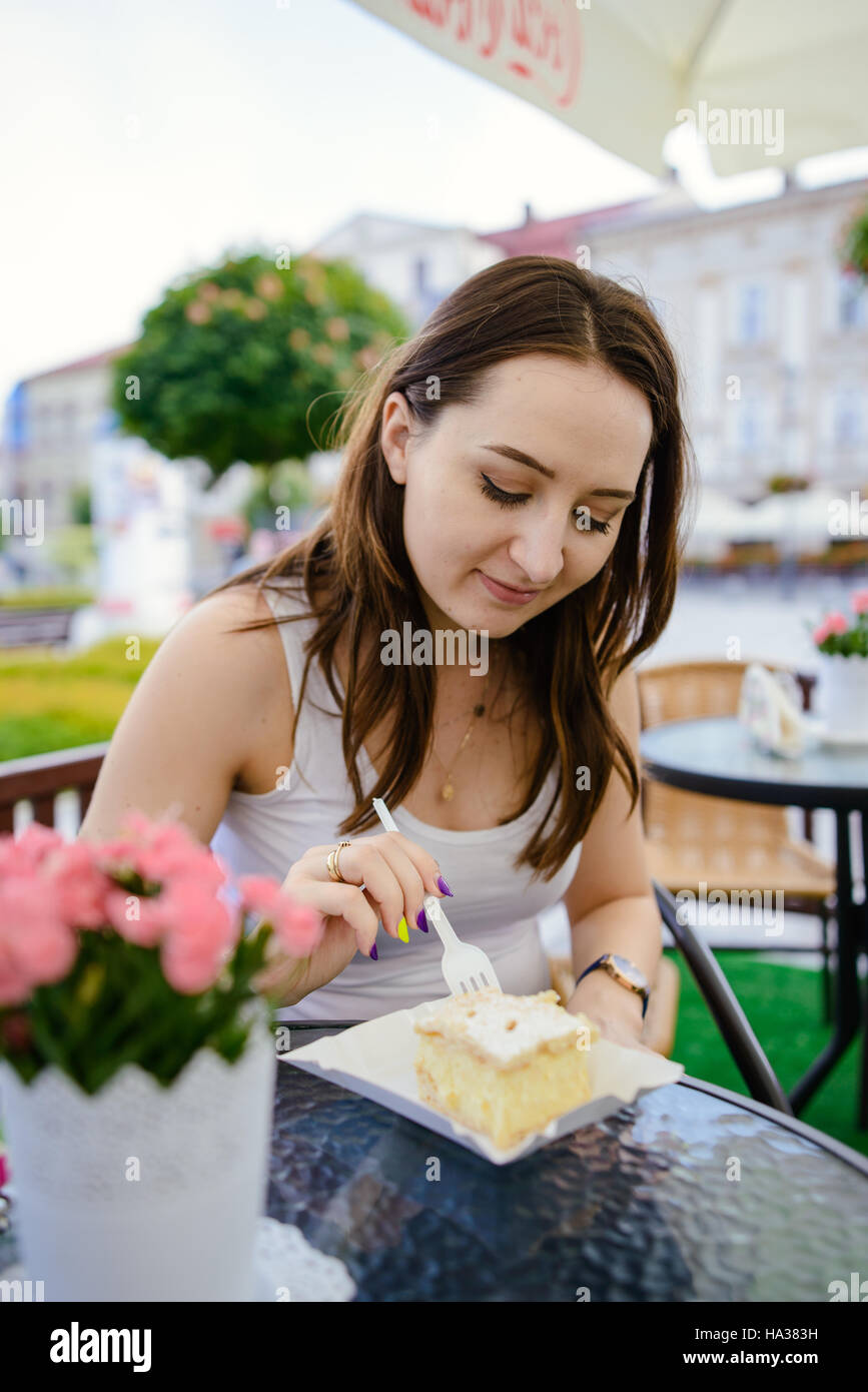 girl eating piece of fondant cake on table, outdoor restaurant Stock ...