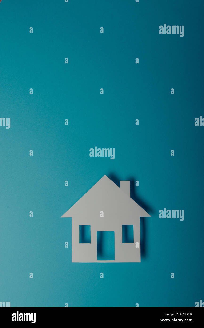 House shaped paper cutout on on blue background Stock Photo - Alamy