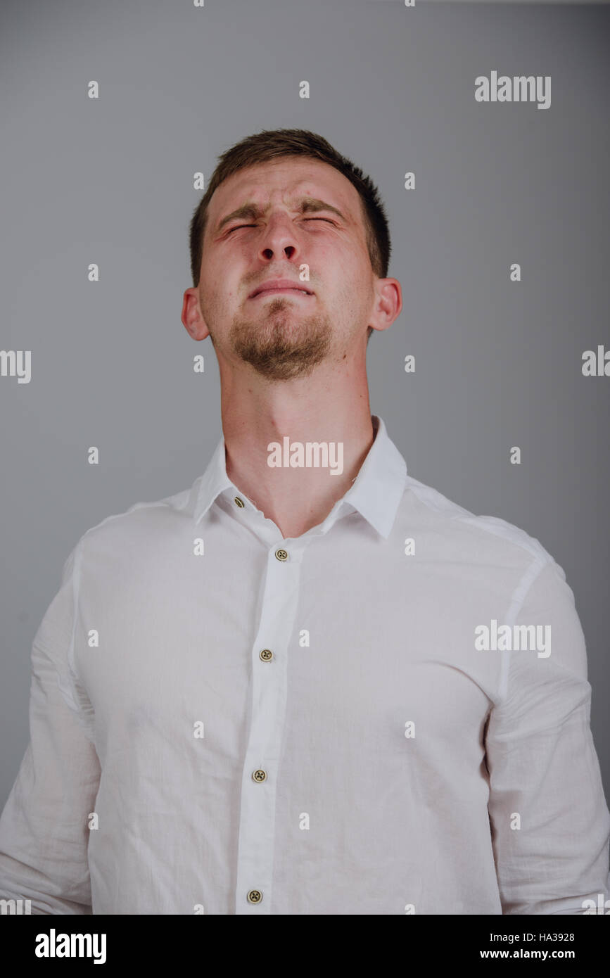 young man with a strong pain against gray background Stock Photo - Alamy
