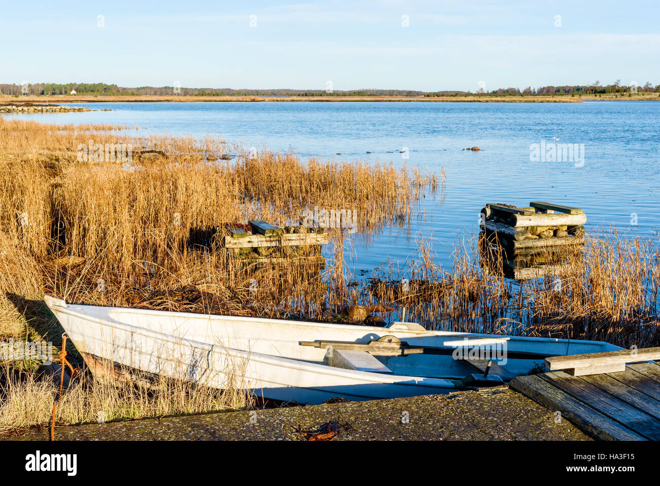 Coastal landscape in fall with white rowboat moored at pier. Location ...