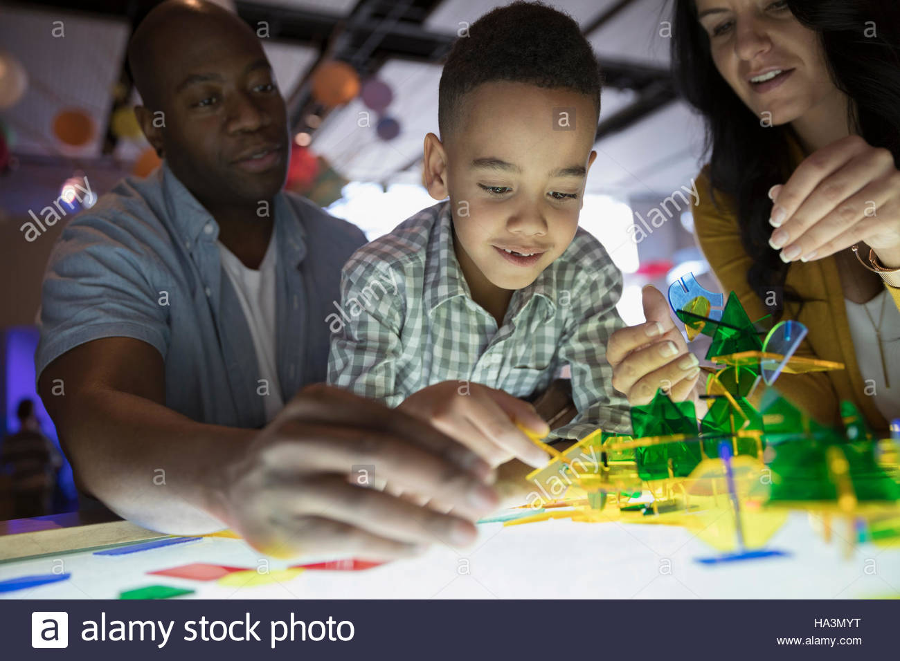 Family playing with shapes at lighted display in science center Stock ...