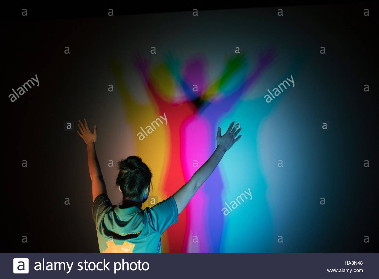 Woman casting multicolor shadows on projection screen in science center ...