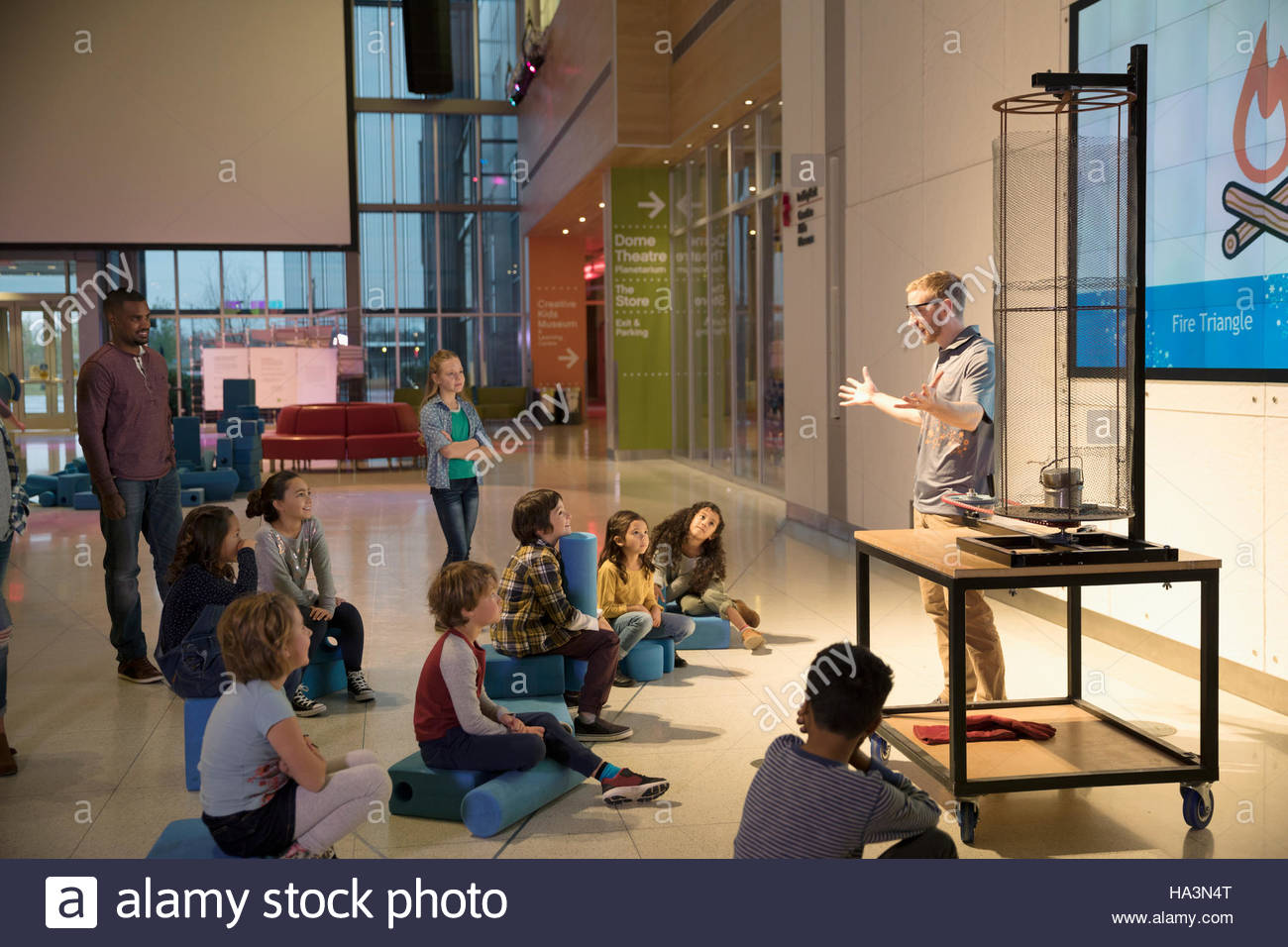 Children watching scientist leading demonstration in science center ...