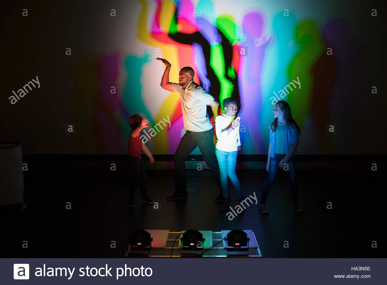 Scientist and children casting multicolor shadows on projection screen ...