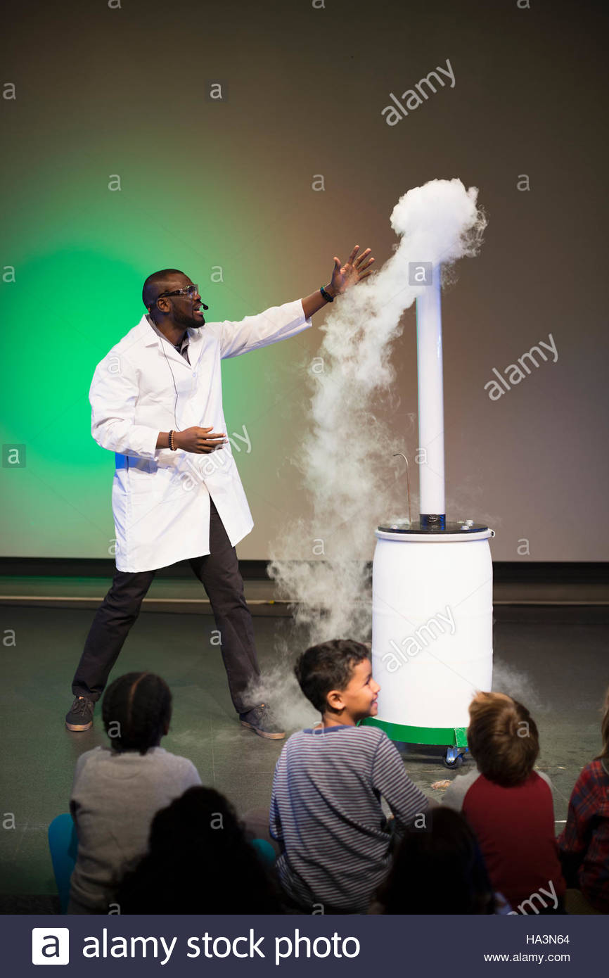 Children watching scientist conducting liquid nitrogen experiment ...