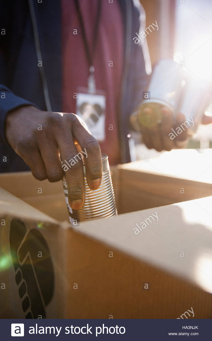 Volunteer packing tin cans into cardboard box Stock Photo - Alamy